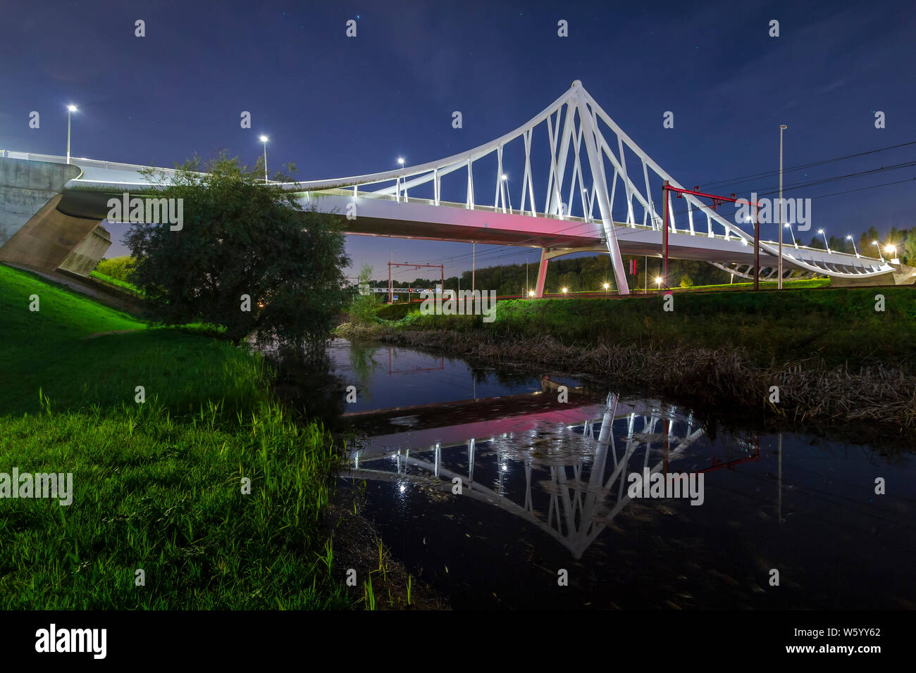 Suspension bridge at night under moonlight with water and reflection ...