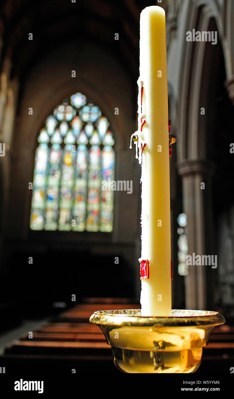Large church candle in dark interior with stained glass window in ...