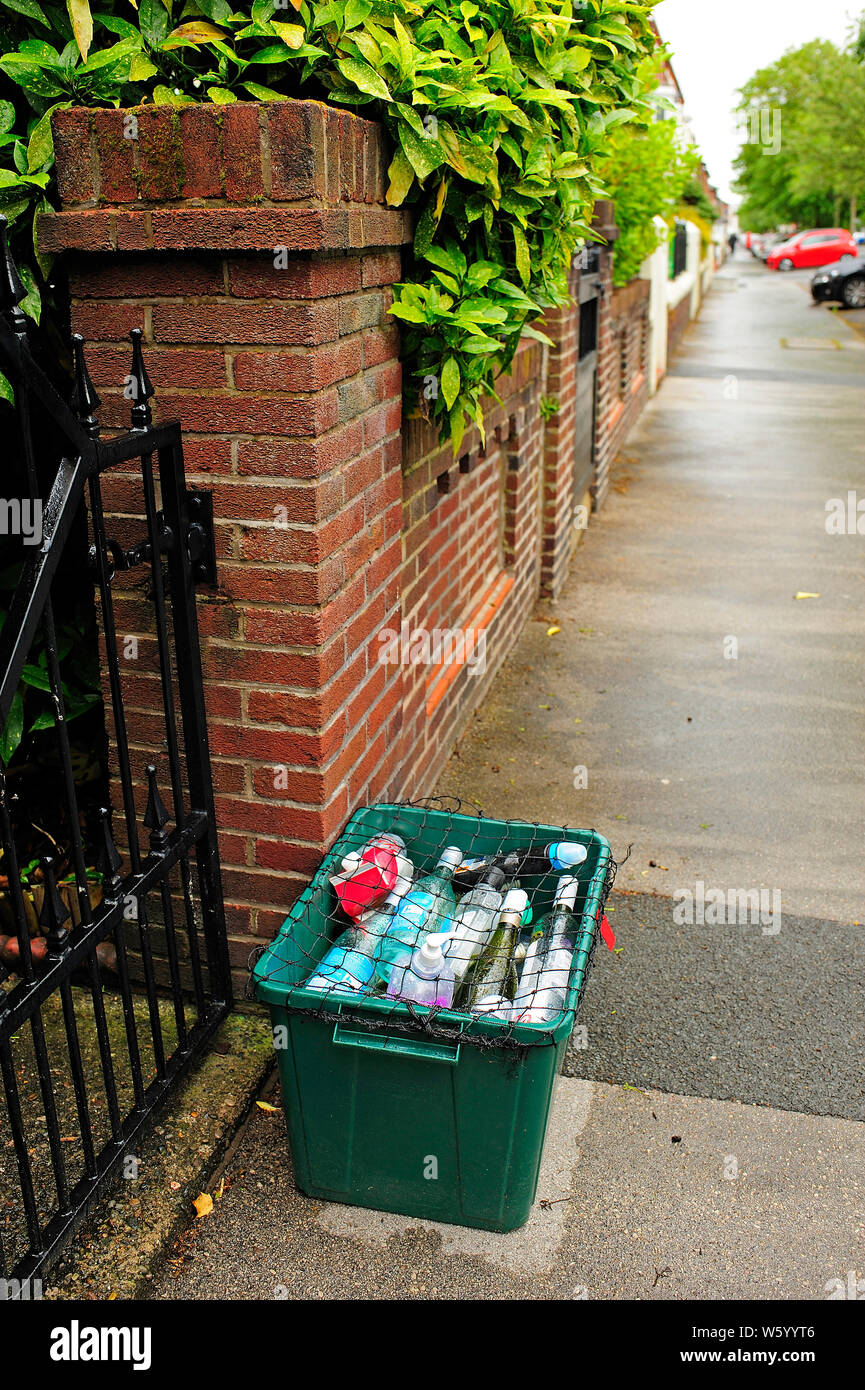 Green plastic bin containing household materials for recycling at gate ...