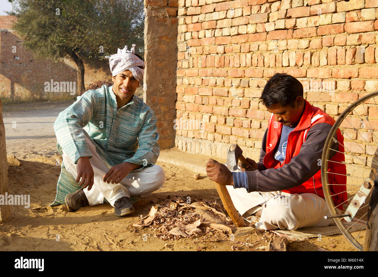 Farmer sitting near blacksmith making a hammer Stock Photo - Alamy