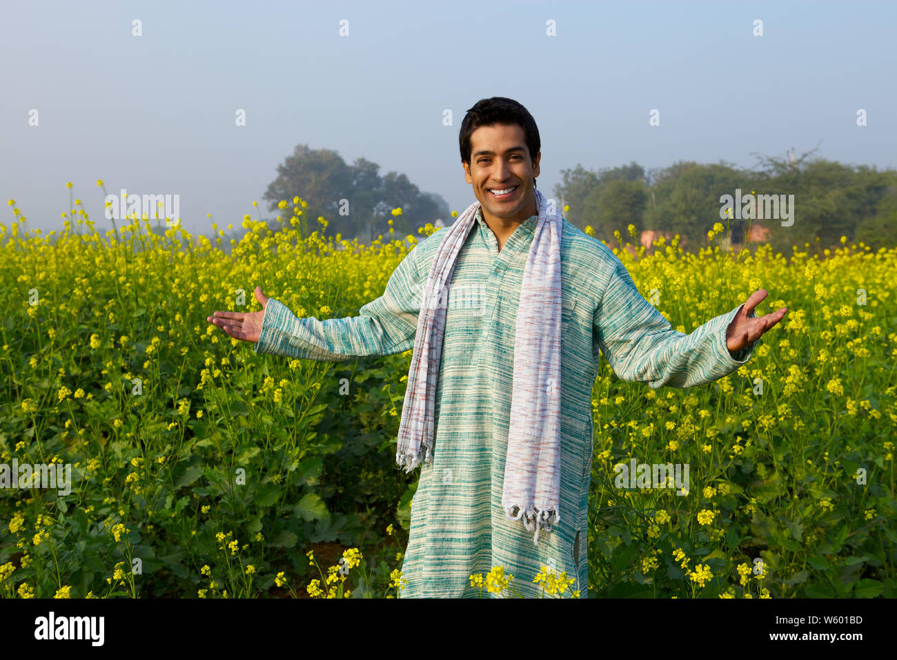 Farmer showing mustard field and smiling Stock Photo - Alamy