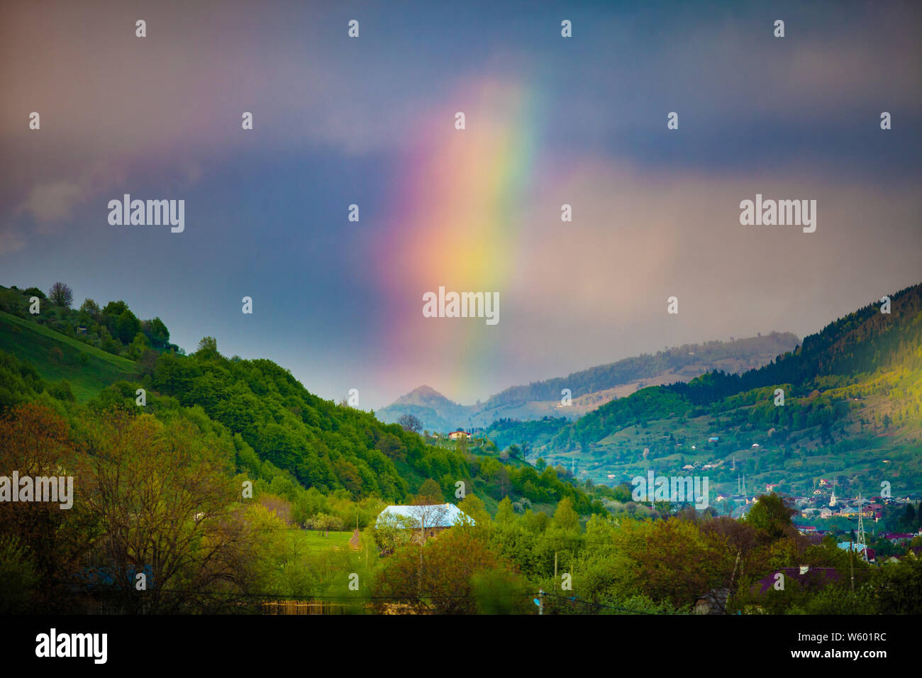 Rainbow over mountain landscape and small house Stock Photo - Alamy
