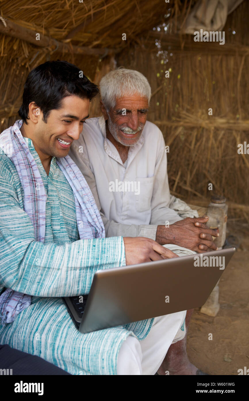 Farmer explaining to villager on a laptop Stock Photo - Alamy