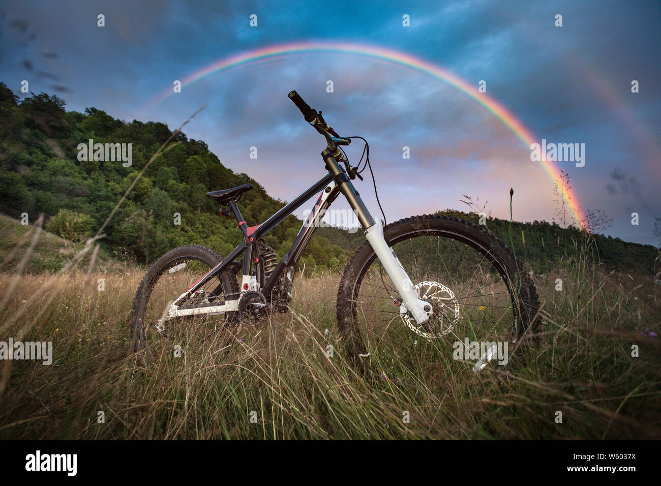 Mountain bike in beautiful nature scene with hills and rainbow Stock ...