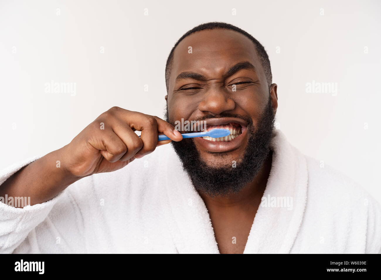 portrait of a happy young dark-anm brushing his teeth with black ...