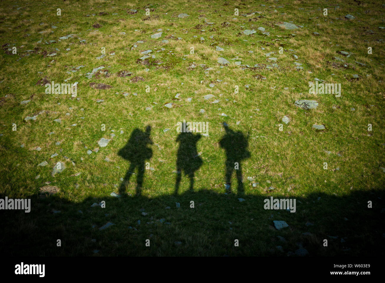 Three hikers shadow on mountain side Stock Photo - Alamy