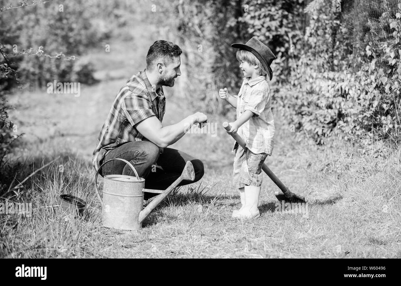 father and son in cowboy hat on ranch. Eco farm. small boy child help ...