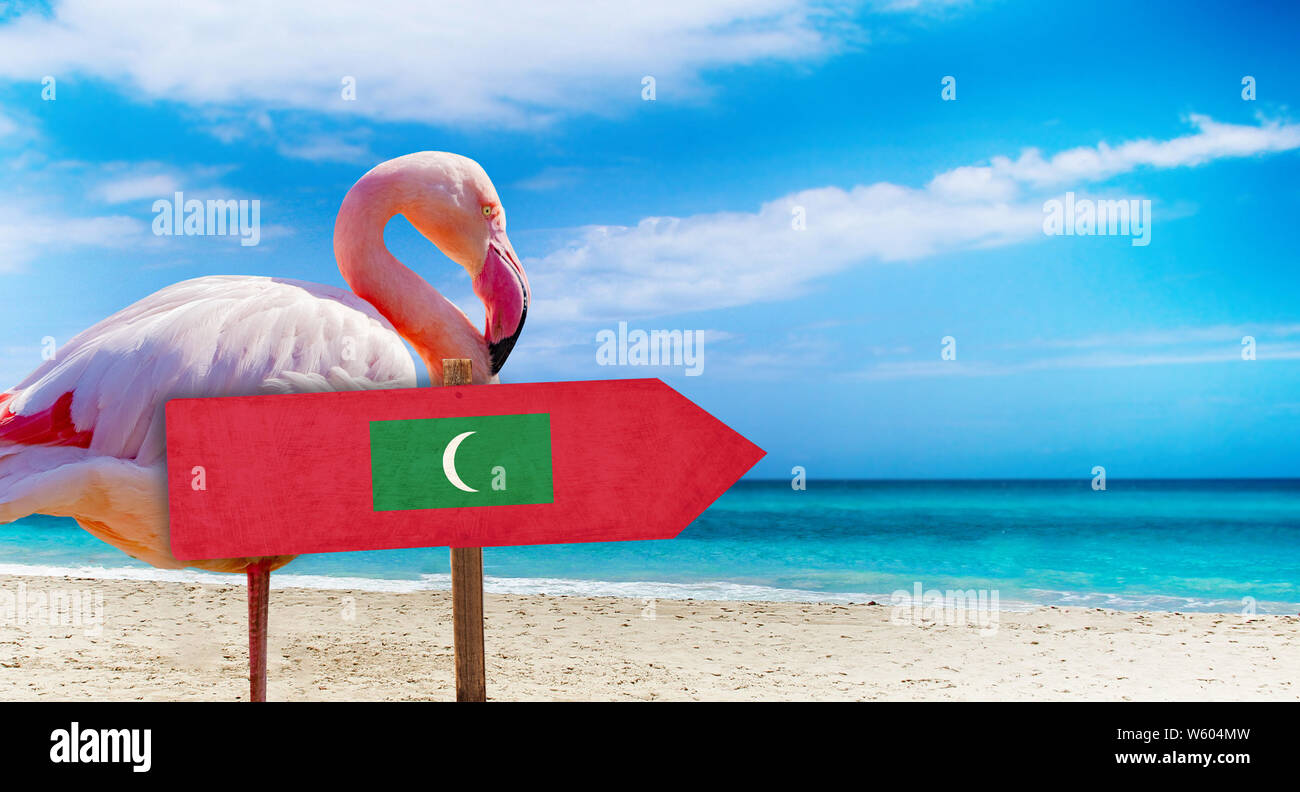 Maldives flag on wooden table sign on beach background with pink ...