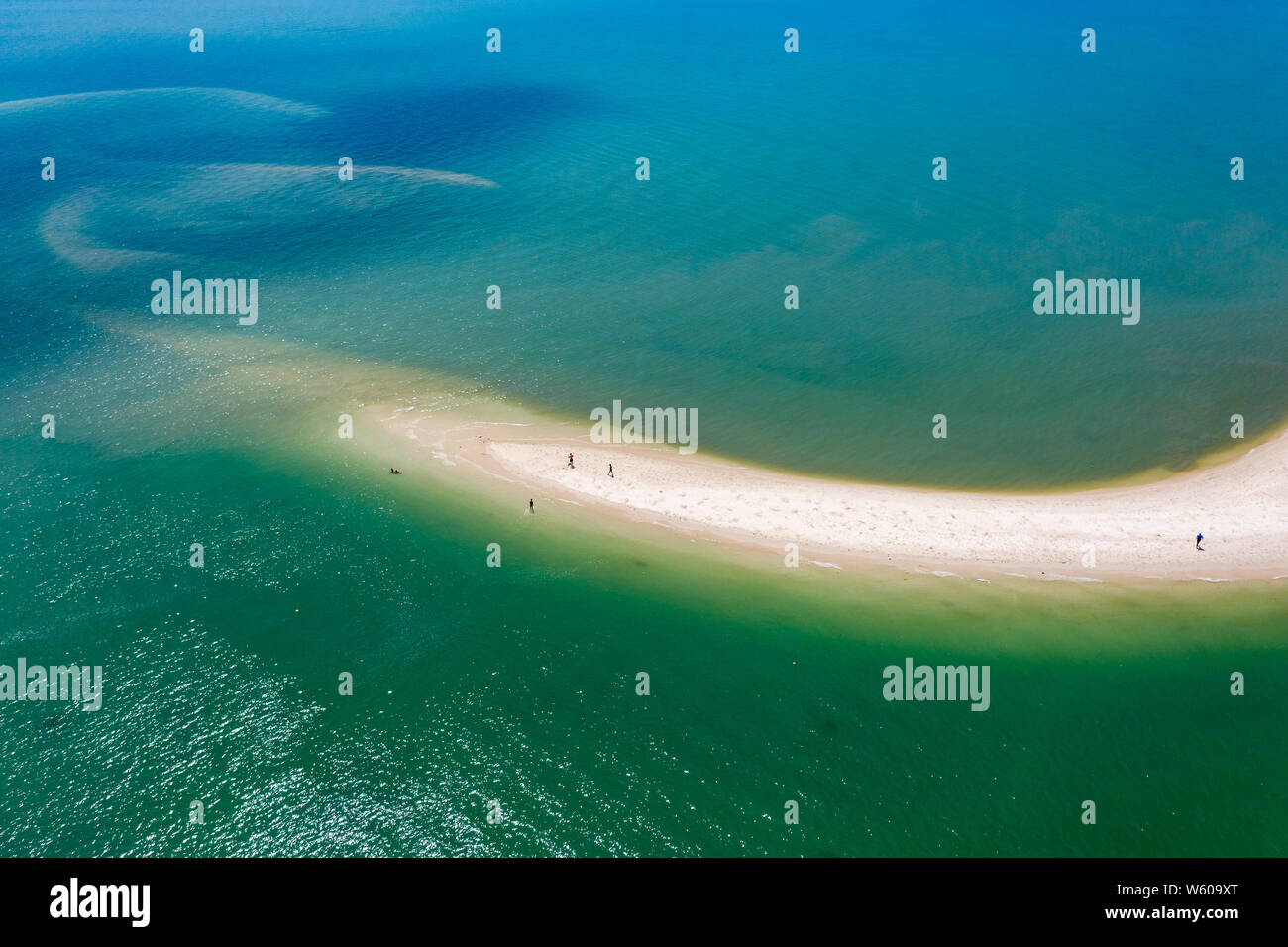 Aerial view of a sand spit leading into the ocean from a green ...