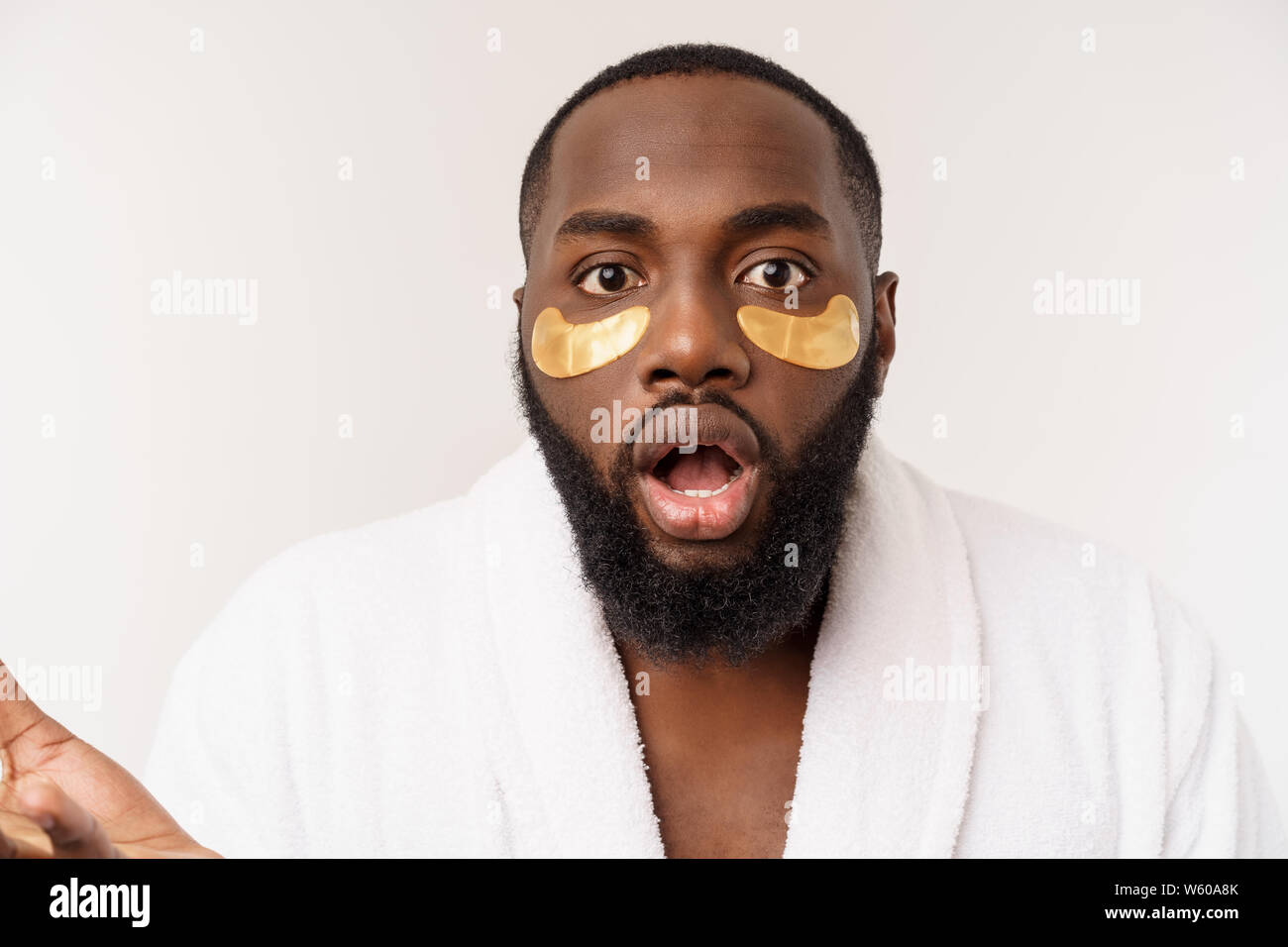 A young man with paper mask on face looking shocked with an open mouth ...