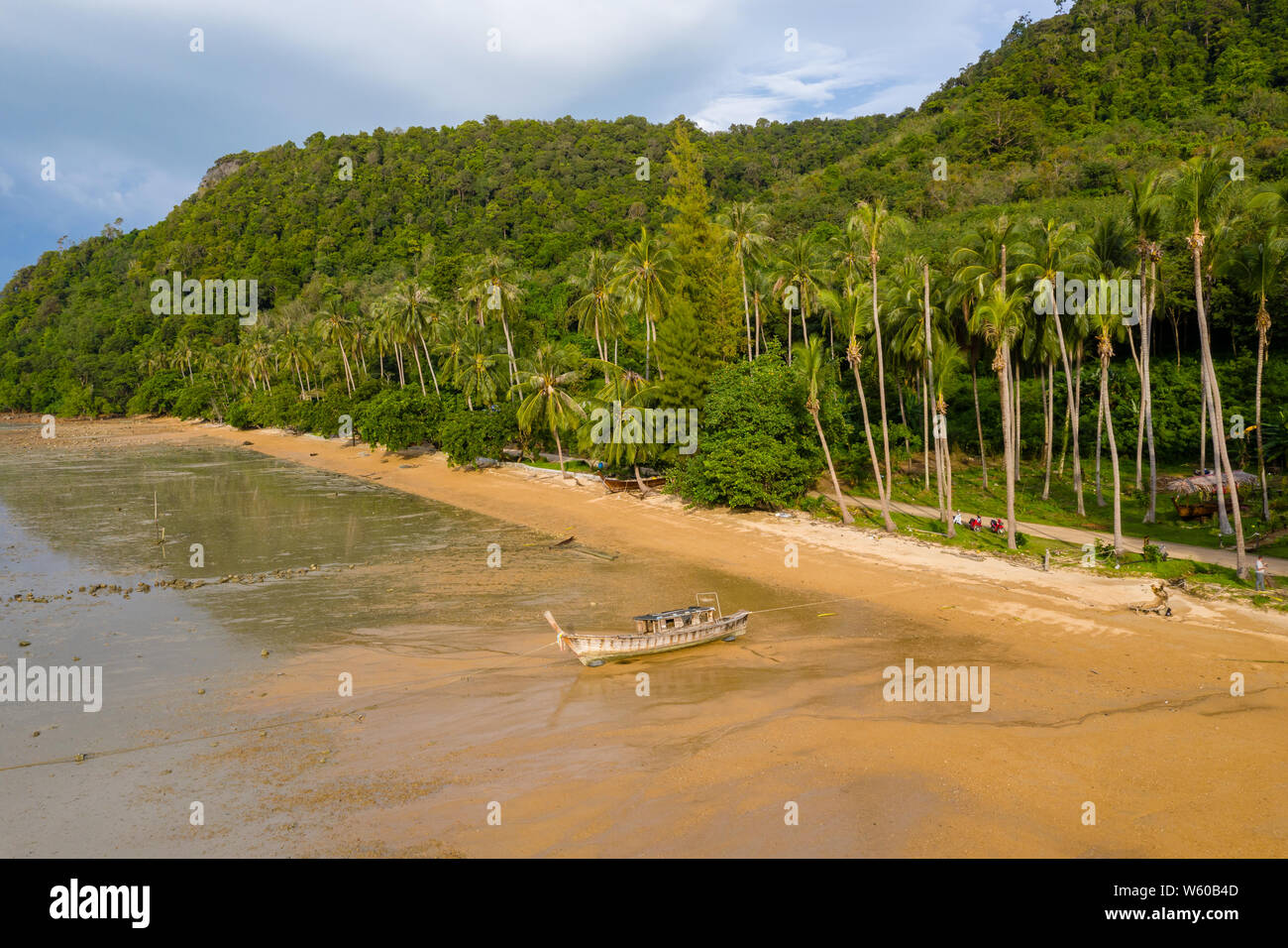 Aerial view of a small wooden boat on a beach at low tide on a tropical ...