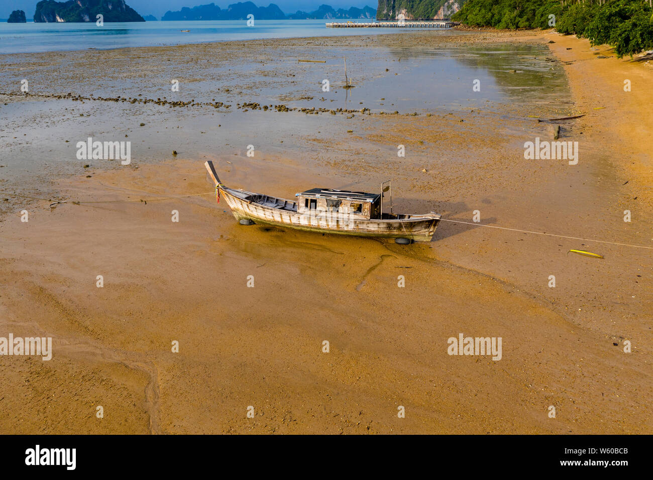 Low aerial view of an old wooden boat stranded at low tide at dusk on a ...