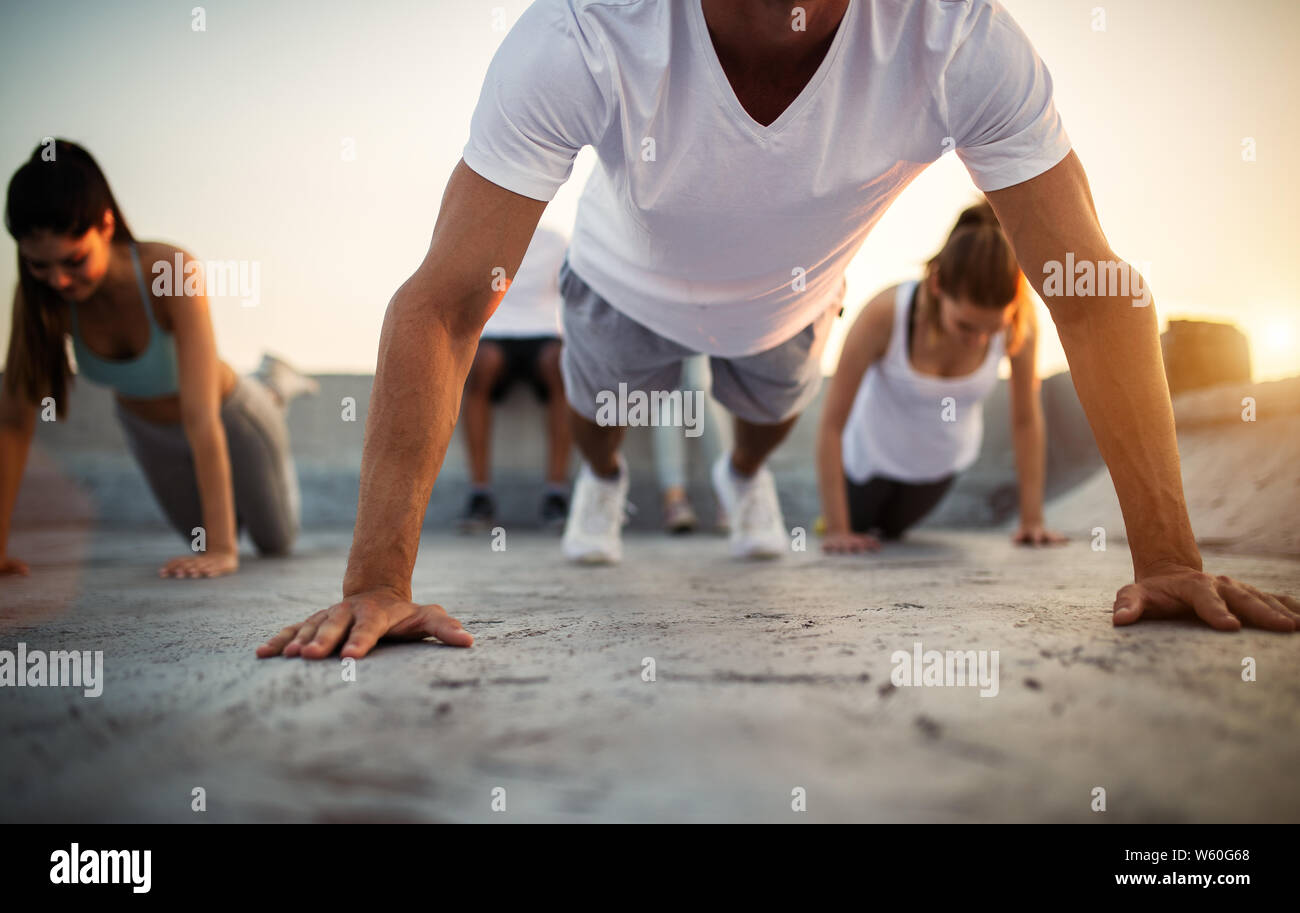 Group of athletic young people, friends in sportswear doing exercises ...