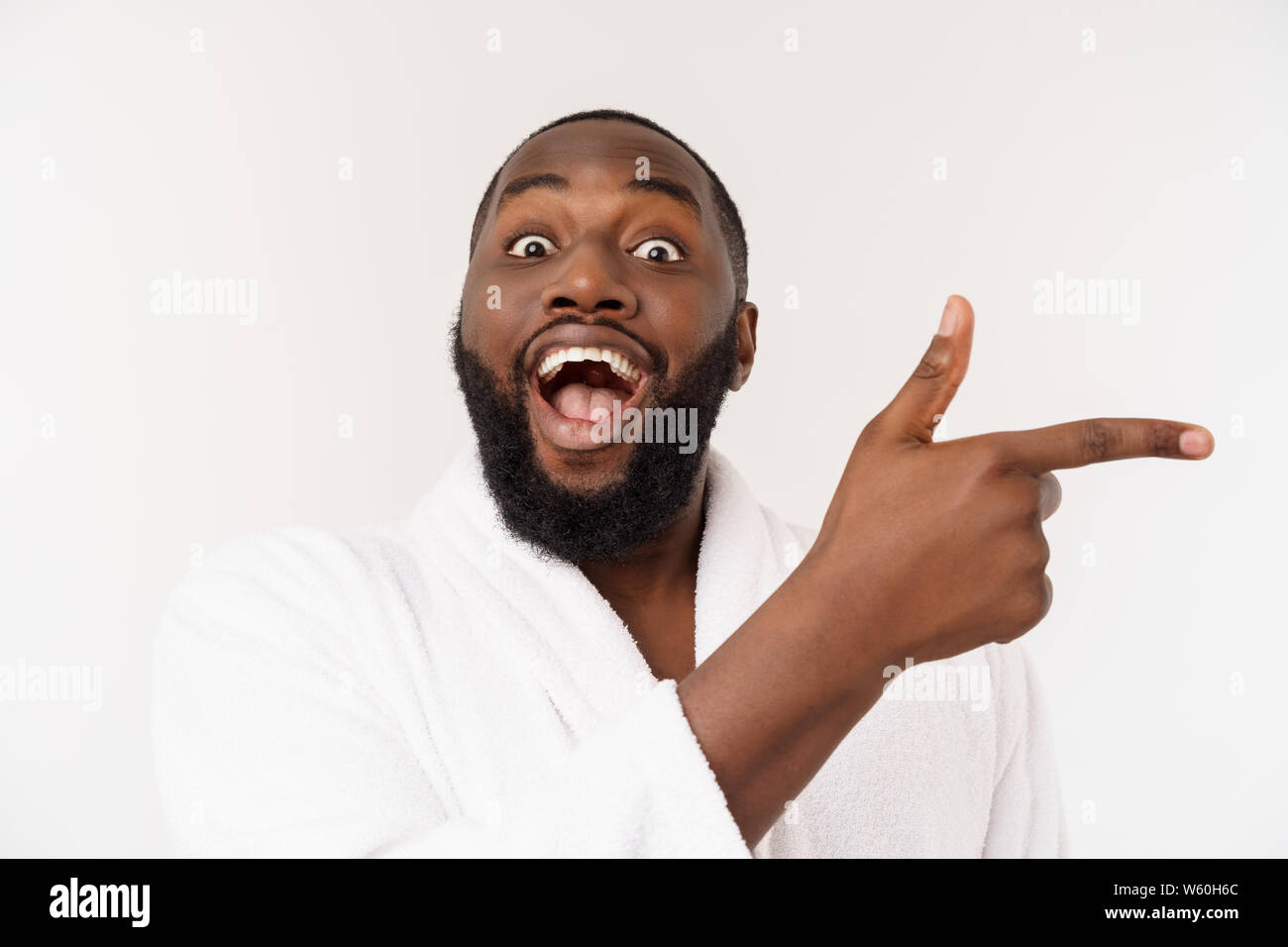 Black guy wearing a bathrobe pointing finger with surprise and happy emotion. Isolated over ...
