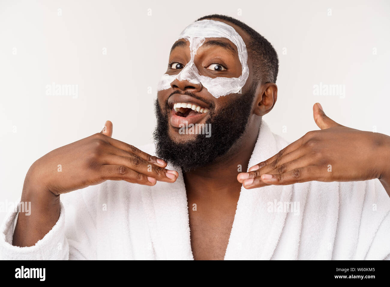 Young african-american guy applying face cream on white background ...