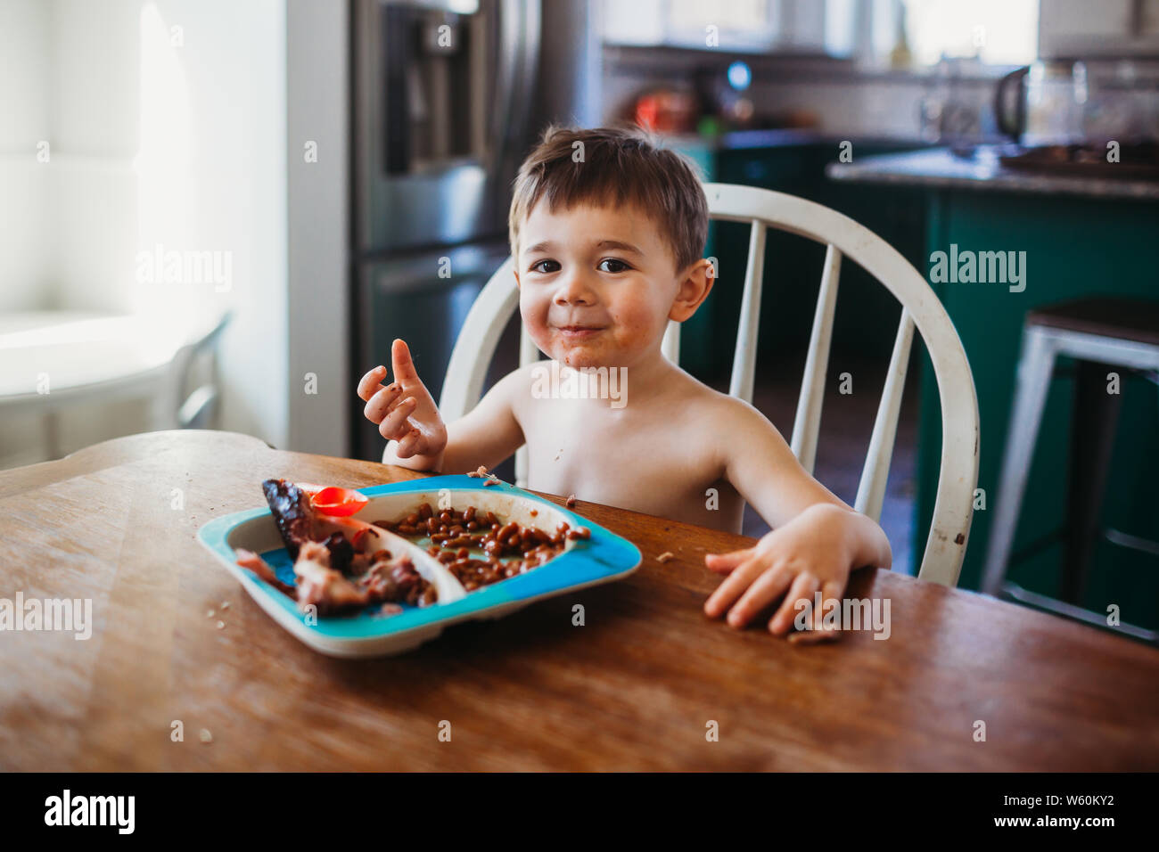 Young boy smiling with eating lunch at dining table Stock Photo - Alamy