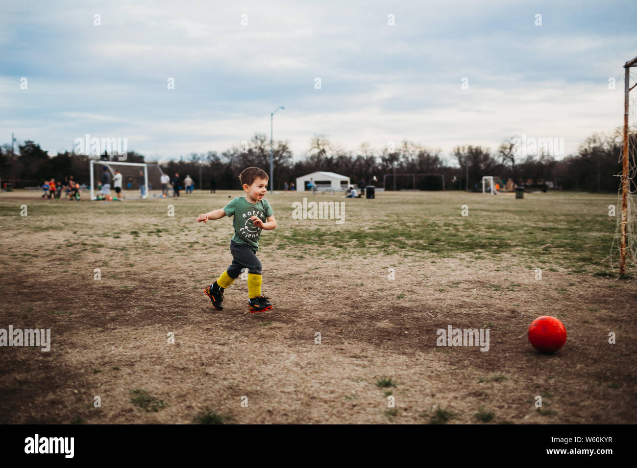 Young boy running towards soccer ball outside Stock Photo - Alamy