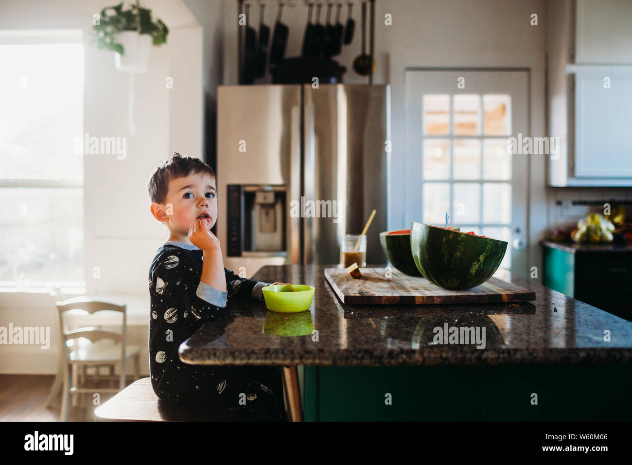 Young boy sitting on stool at kitchen counter eating watermelon Stock ...
