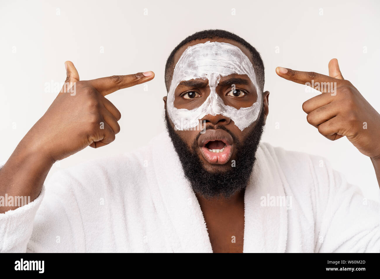 A young man with paper mask on face looking shocked with an open mouth ...