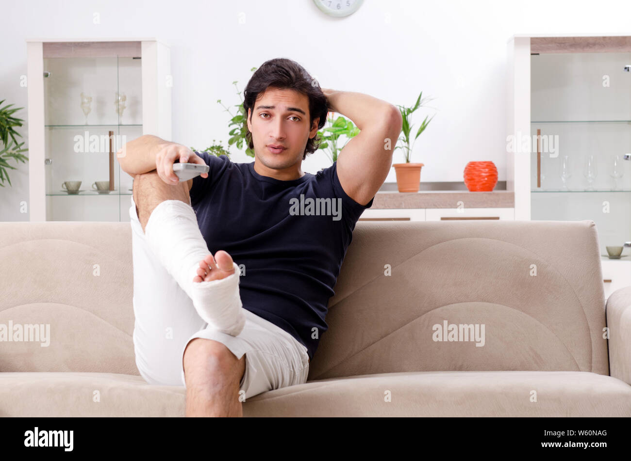 The leg injured young man suffering at home Stock Photo - Alamy
