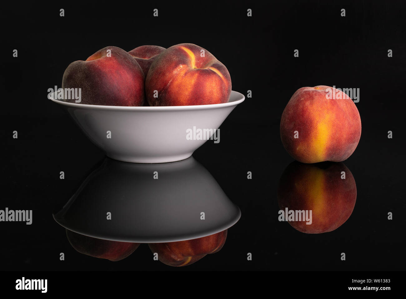 Group of four whole fresh red peach in a white ceramic bowl isolated on ...