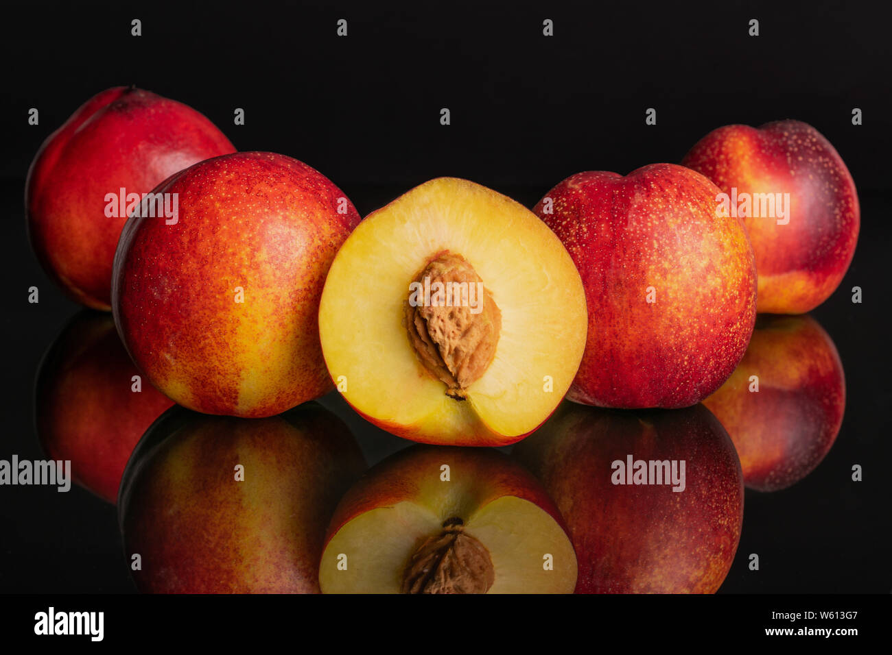 Group of four whole one half of fresh red nectarine isolated on black ...