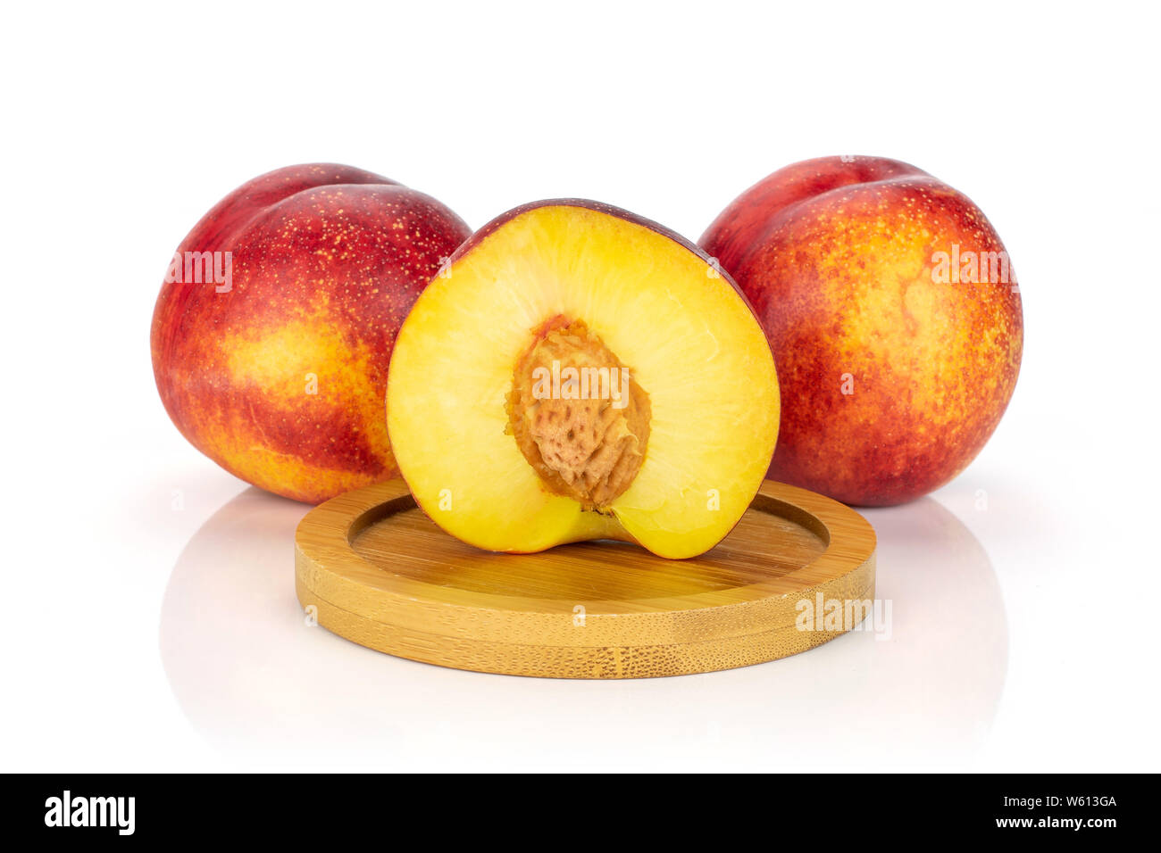 Group of two whole one half of fresh red nectarine on a round bamboo ...
