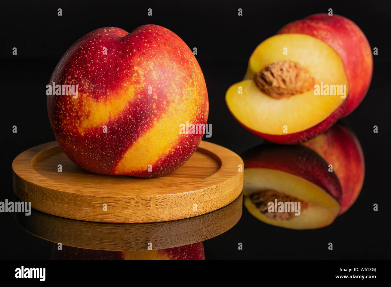 Group of two whole one half of fresh red nectarine on a round bamboo ...
