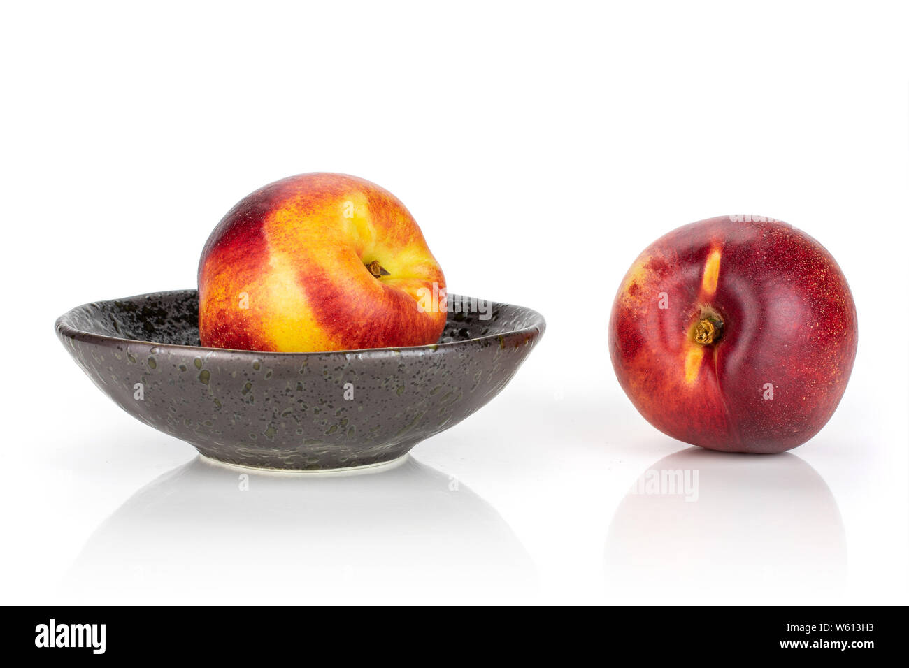 Group of two whole fresh red nectarine one is aside and the other is in ...