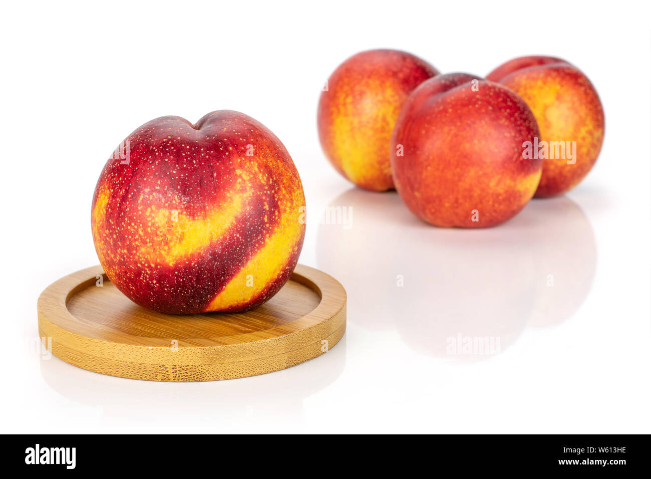 Group of four whole fresh red nectarine on a round bamboo coaster ...