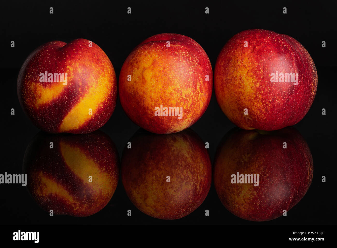 Group of three whole fresh red nectarine in a row isolated on black ...