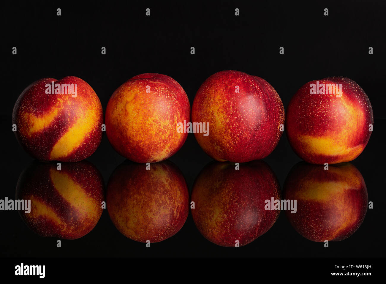 Group of four whole fresh red nectarine in a row isolated on black ...