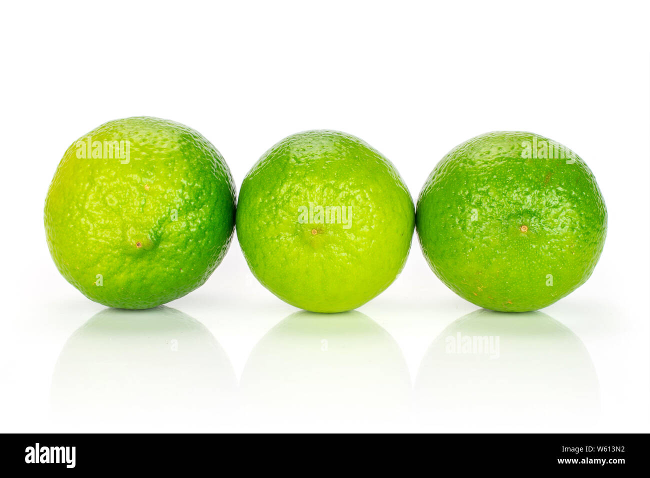 Group of three whole fresh green lime placed in a row isolated on white ...