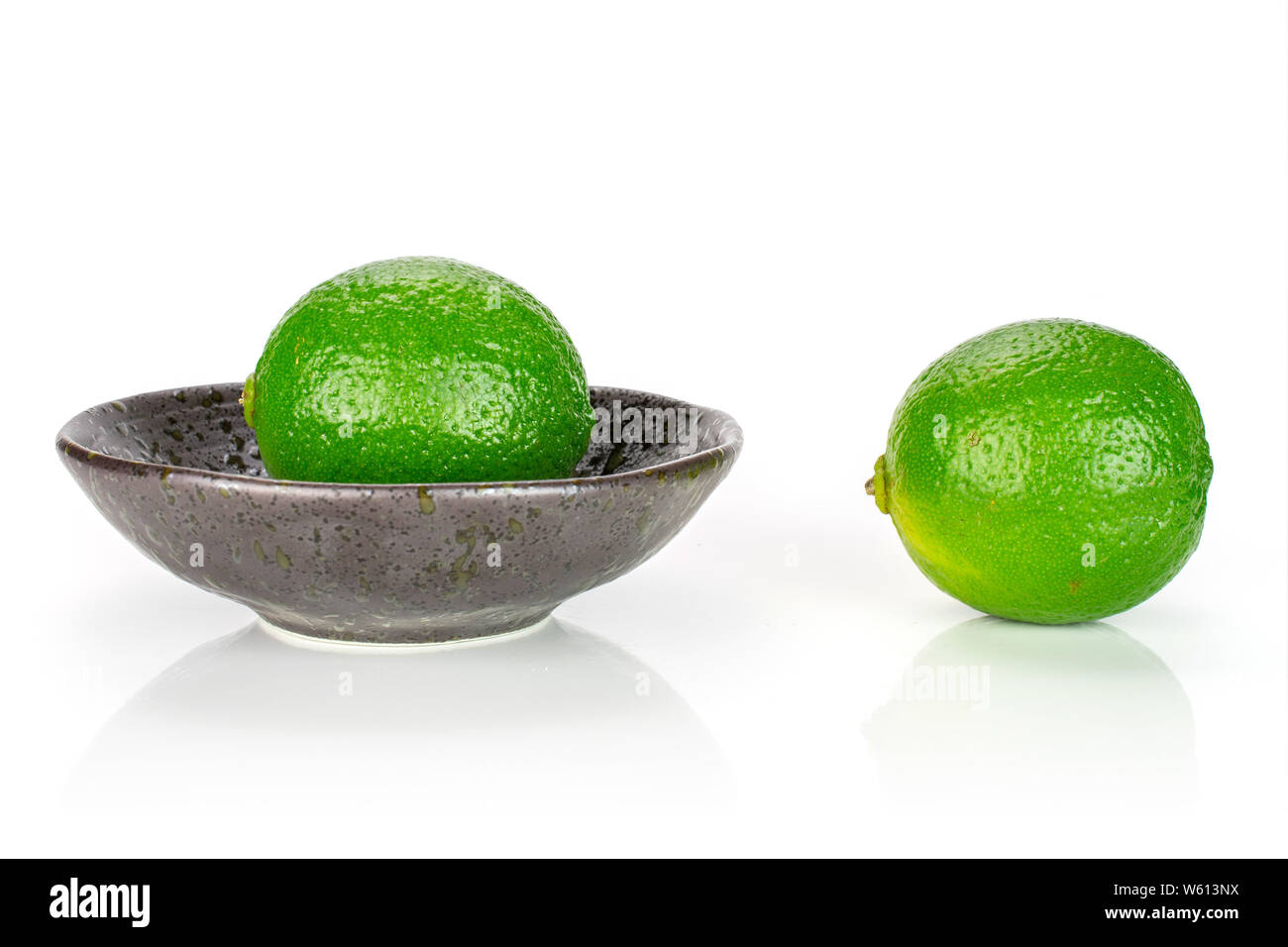 Group of two whole fresh green lime one is aside and the other is in a ...