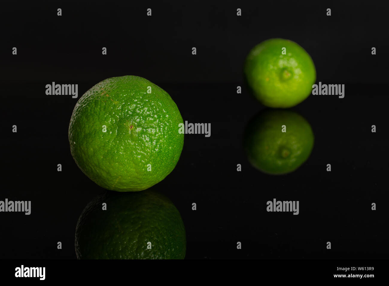 Group of two whole fresh green lime one is in the front isolated on ...