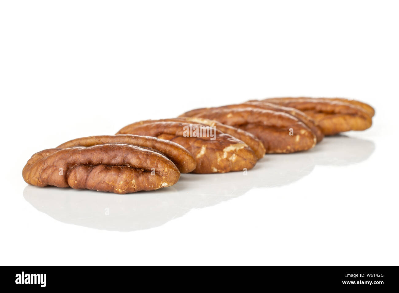 Group of four whole fresh brown pecan nut half in row isolated on white ...