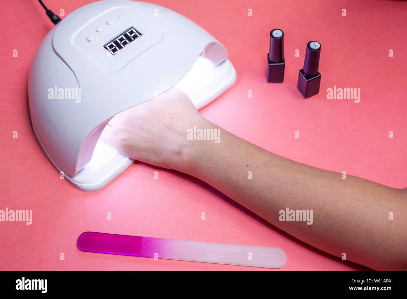 A young woman at manicure procedure. Woman Nail Polish process. Female ...