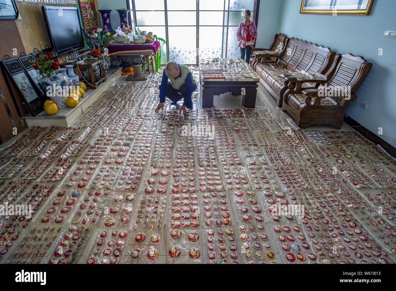 Chinese elderly man Huang Junde displays badges of the portrait of late ...