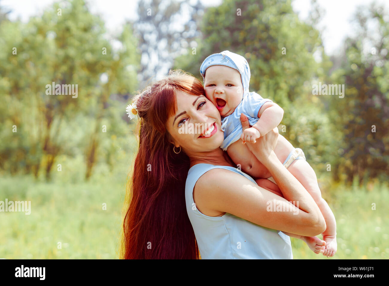 A young mother raised her baby in her arms Stock Photo - Alamy