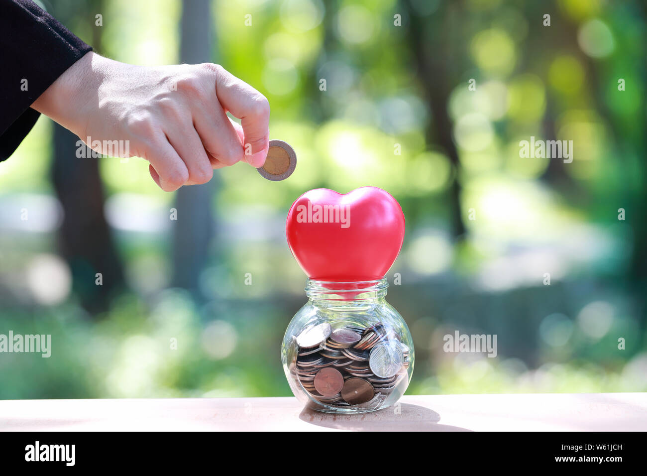 human hands saving money with red heart symbol sign Stock Photo - Alamy