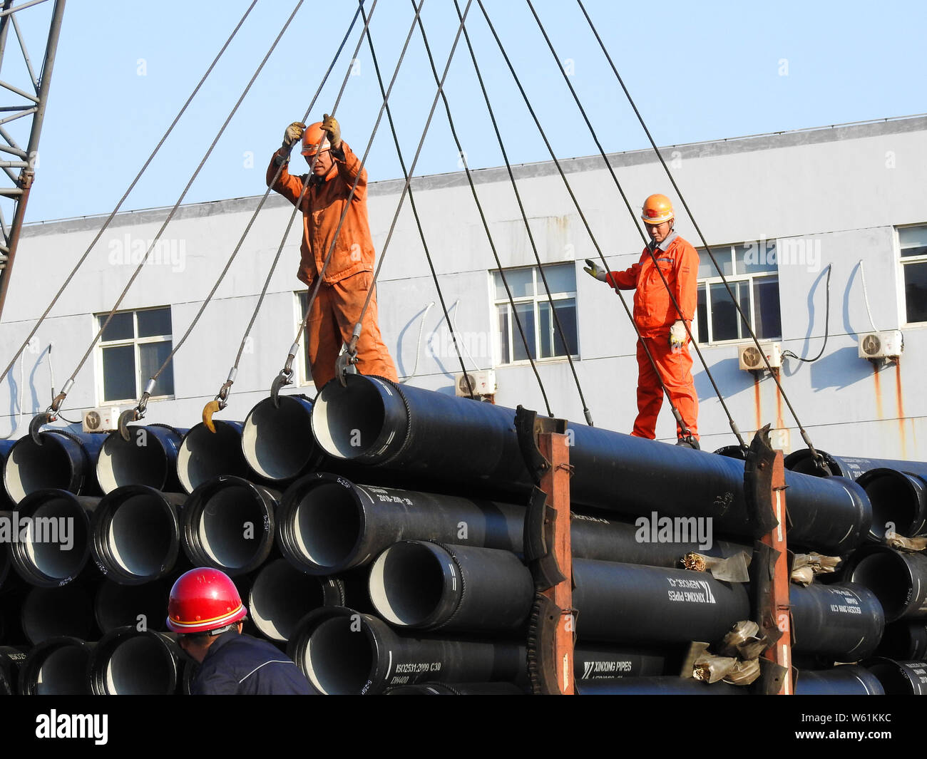 Chinese workers directs a crane to load steel tubes to be exported onto ...