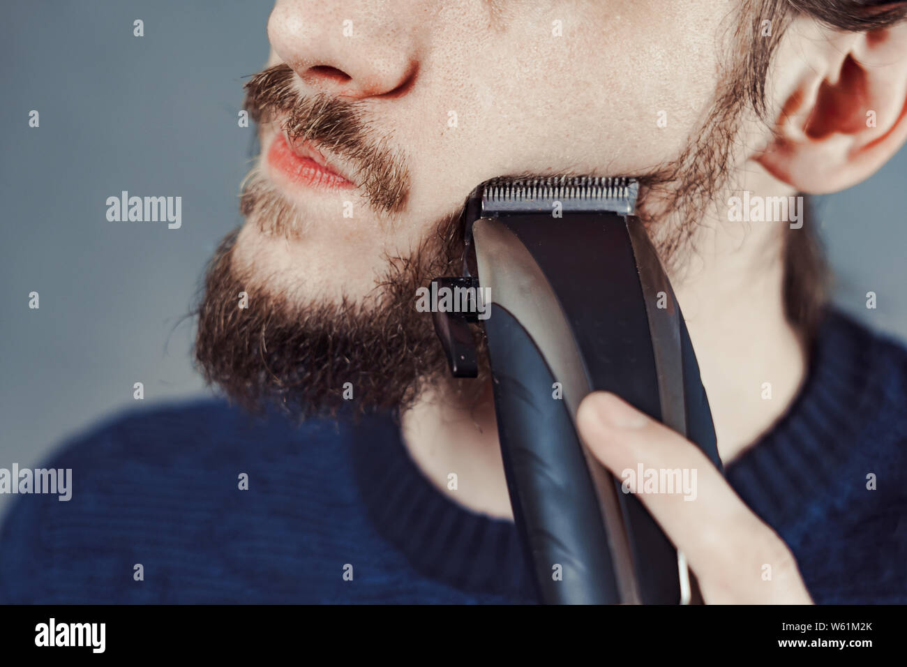 guy shaves his beard with an electric razor Stock Photo - Alamy