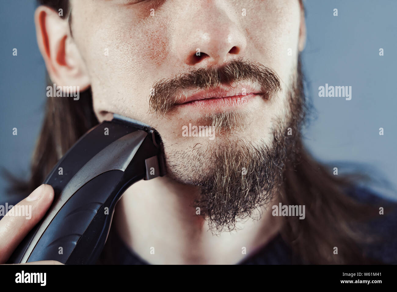 guy shaves his beard with an electric razor Stock Photo - Alamy
