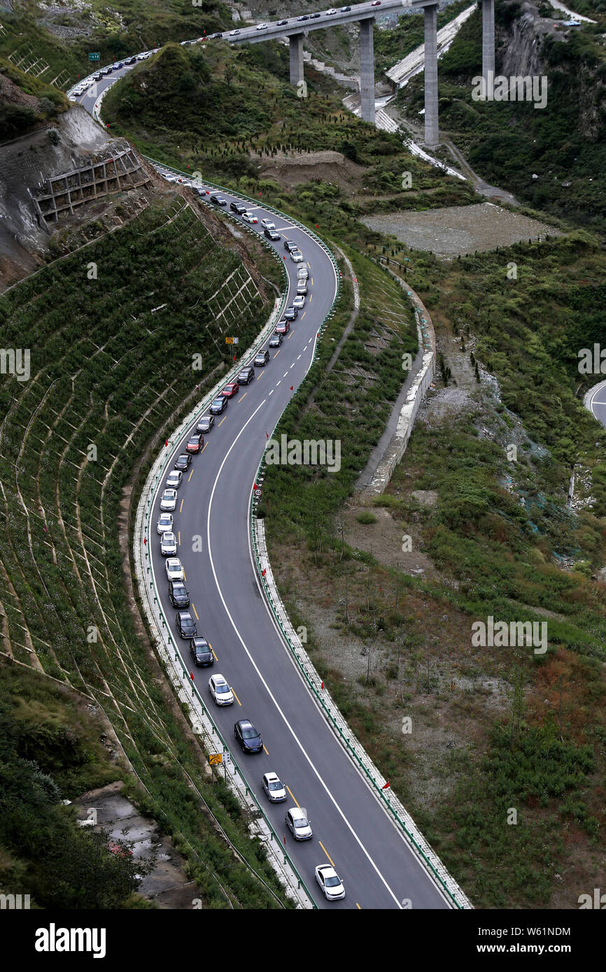 Vehicles travel along the winding mountain road on the Yakang (Ya'an ...