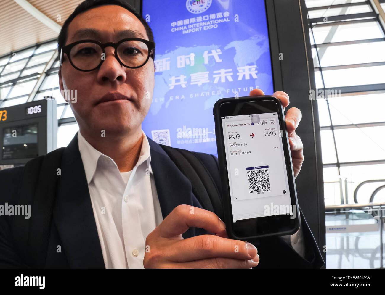 A passenger shows the QR code to be scanned for check-in on his ...