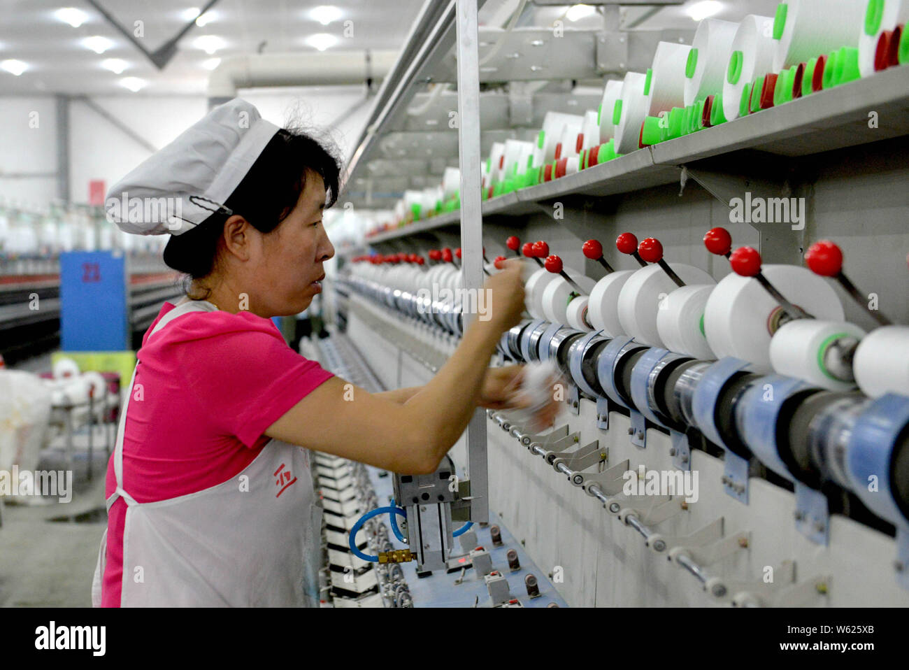 --FILE--A female Chinese worker handles production of yarn at a textile factory in Xiayi county ...