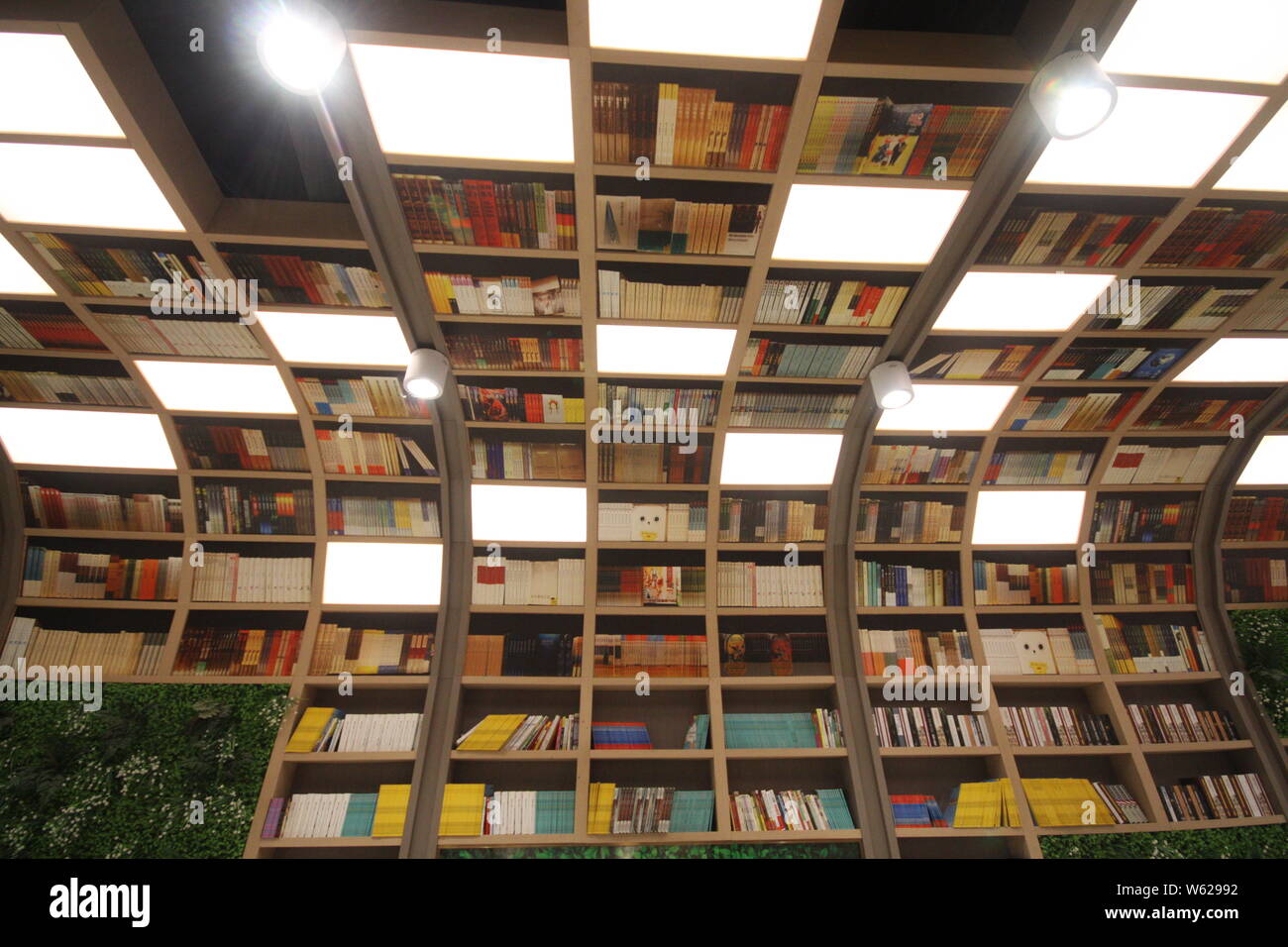 A 10-meter-tall books wall is formed by thousands of books on shelves ...