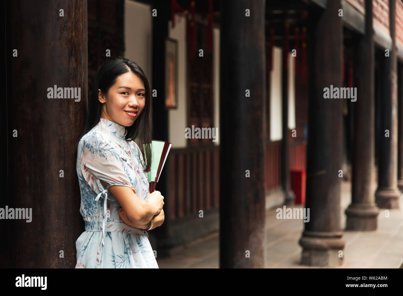 Asian woman in a temple holding a hand fan portrait Stock Photo - Alamy