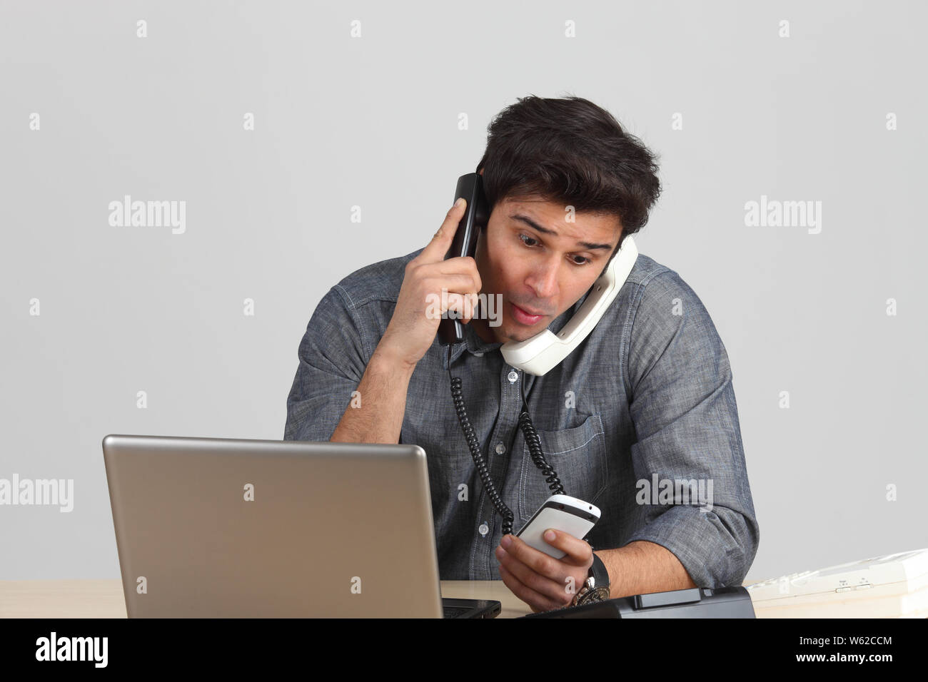 Businessman showing surprised while using multiple phones and laptop ...