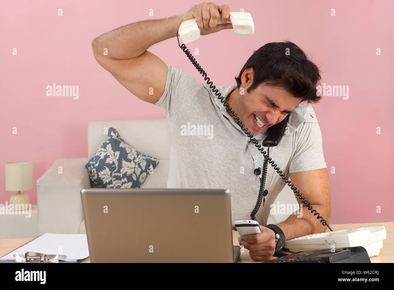 Man showing frustration while using multiple phones and laptop Stock ...